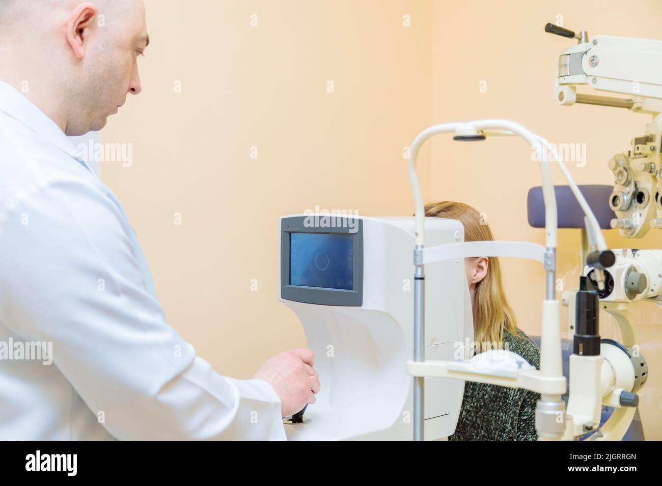 A male ophthalmologist checks the eyesight of a young girl using a ...