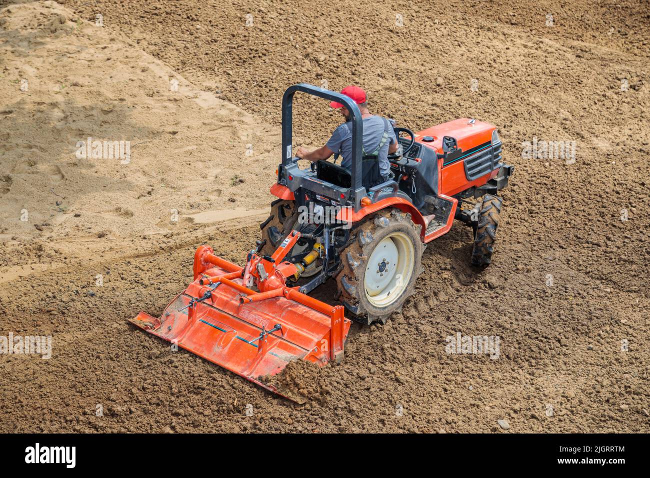 A farmer on a mini tractor loosens the soil for the lawn. Land ...