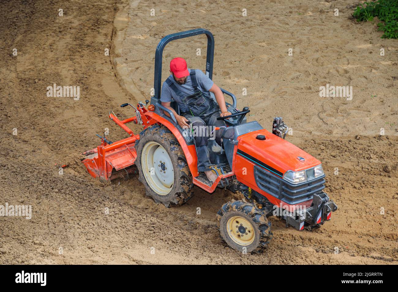 A farmer on a mini tractor loosens the soil for the lawn. Land ...