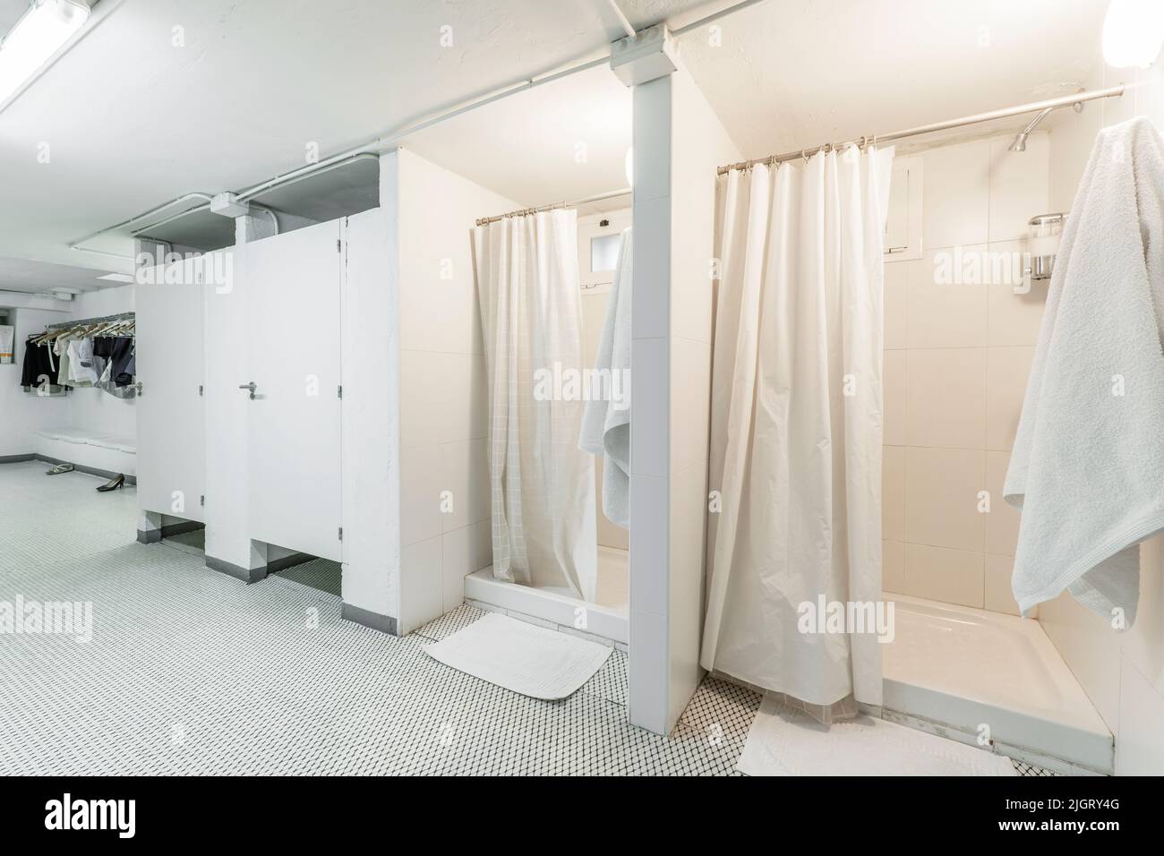 Showers with curtains, toilets with doors and a changing area in a locker room Stock Photo - Alamy