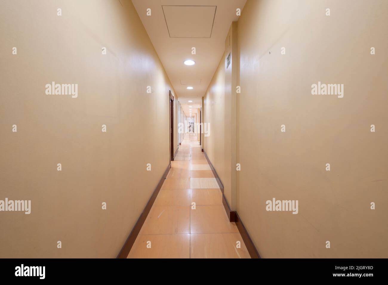 Long corridor painted in smooth cream color with entrance to several ...