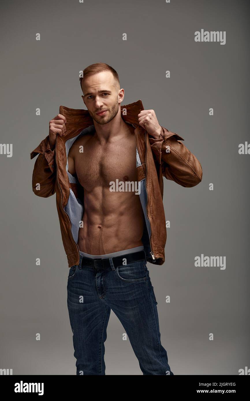 An attractive white man in jeans and black shirts tands in full growth ...