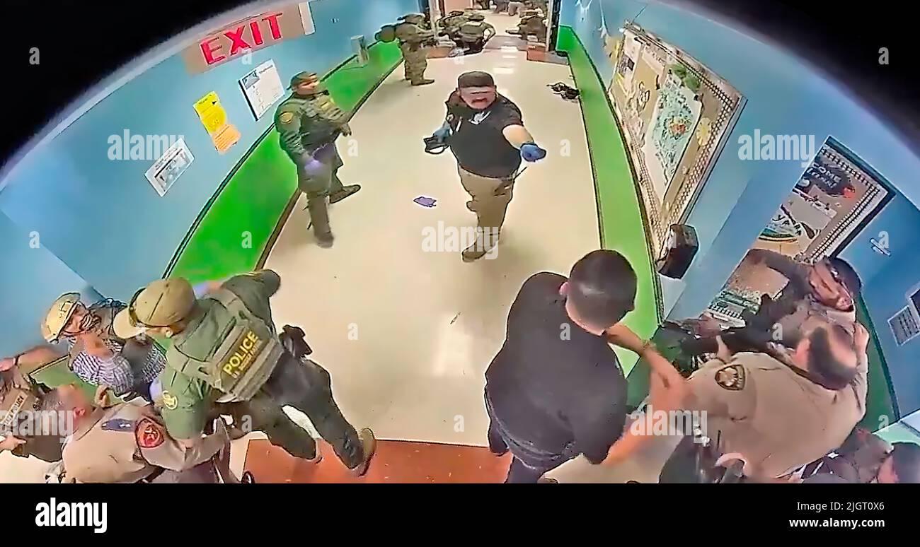 A frame from a school surveillance video shows multiple police officers ...