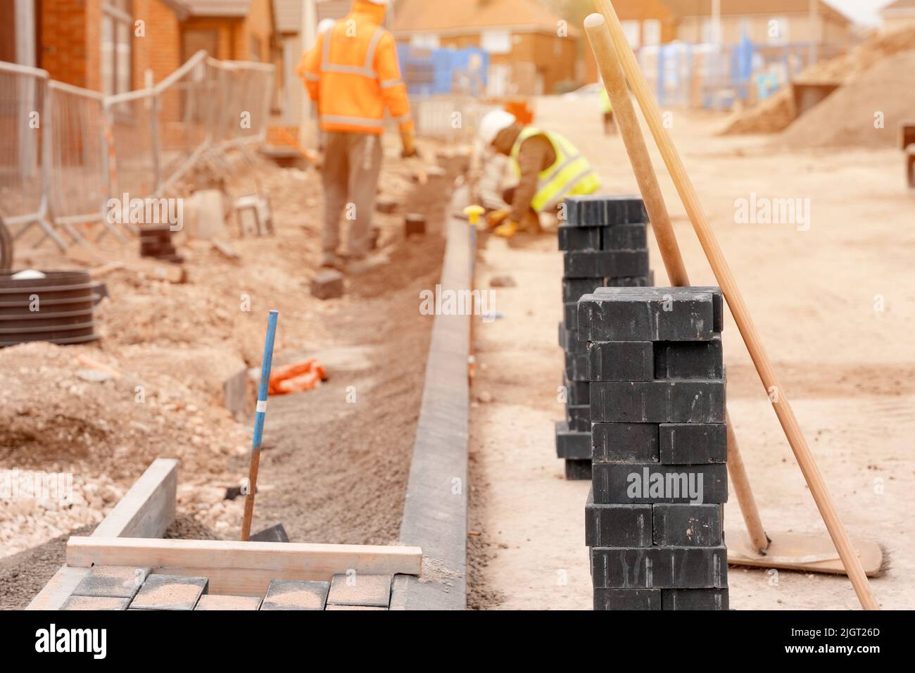 Builders installing paving blocks during road and footpath construction ...