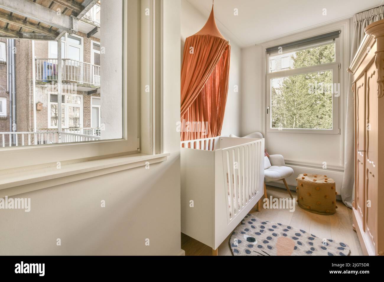 Interior of white room with baby crib and armchair near window with ...