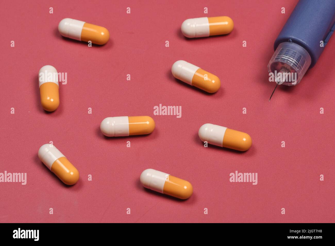 yellow and white medicine capsules on red background and insulin pen ...