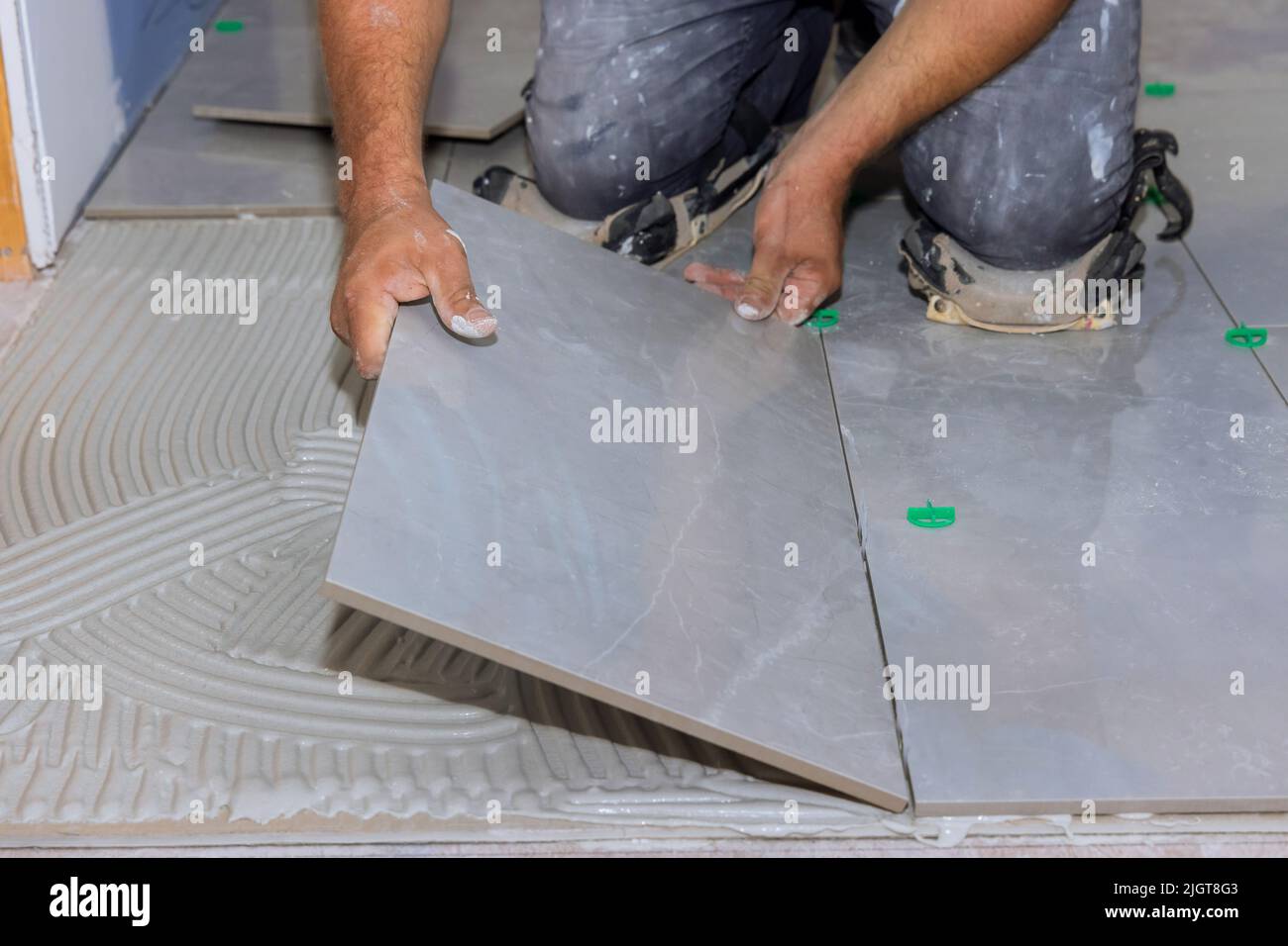 Working on an adhesive surface while installing ceramic floor tiles ...