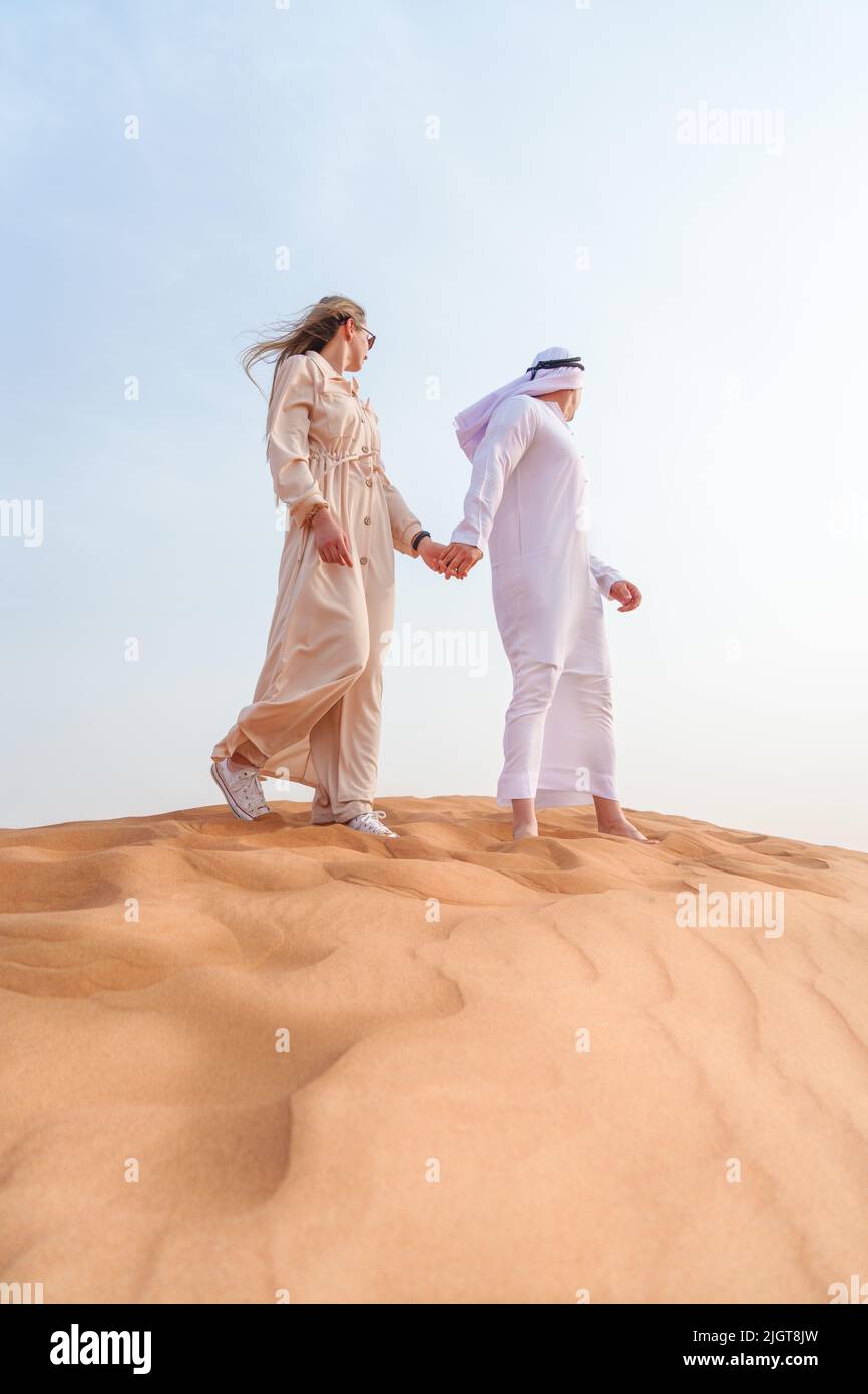 A White couple walking in a desert wearing abayas Stock Photo - Alamy