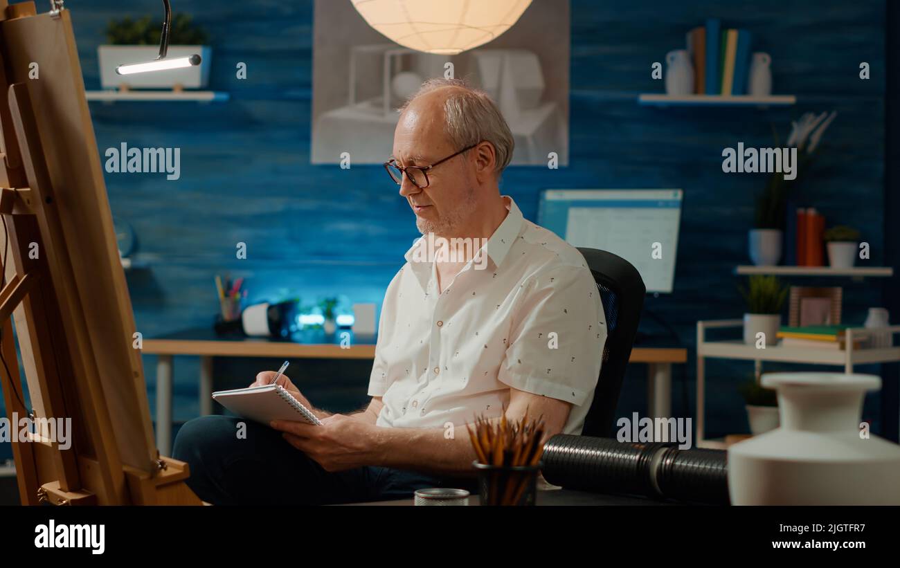 Male artist taking notes on textbook and sketching vase model to draw ...