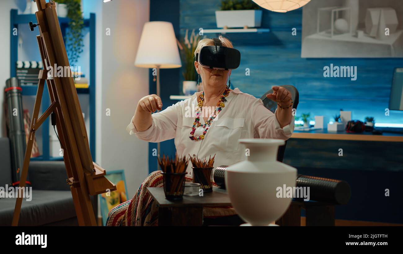 Senior woman using vr glasses with augmented reality to create drawing ...