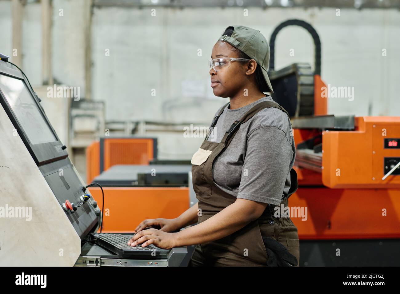 African female operator in workwear concentrating on her work about ...