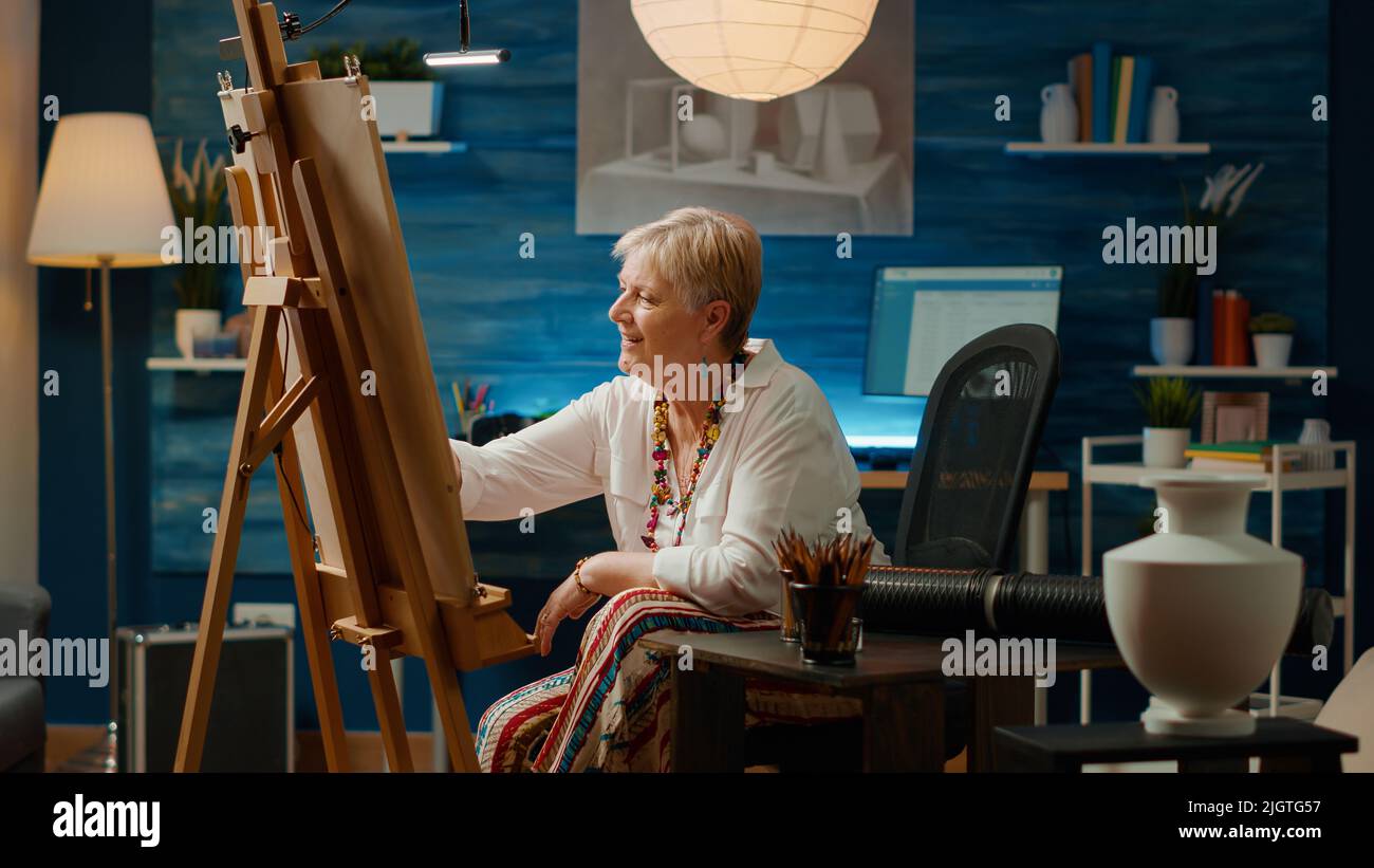 Old woman with creative skills drawing vase model on canvas, using ...