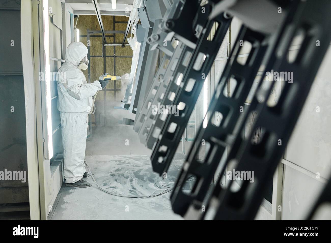 Painter in protective coveralls working to painting the steel structure ...