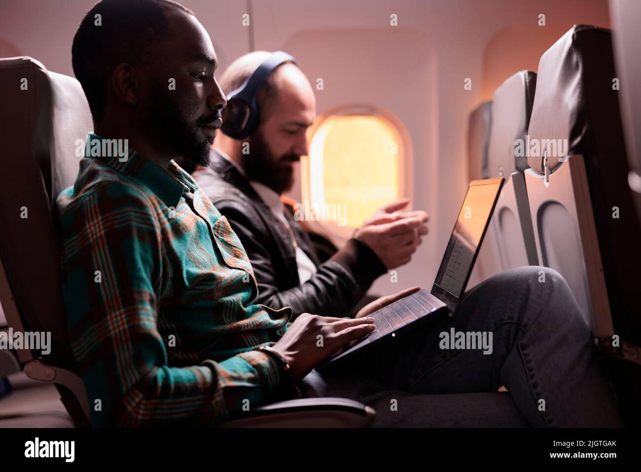 Young freelancer travelling on work trip by airplane in economy class ...