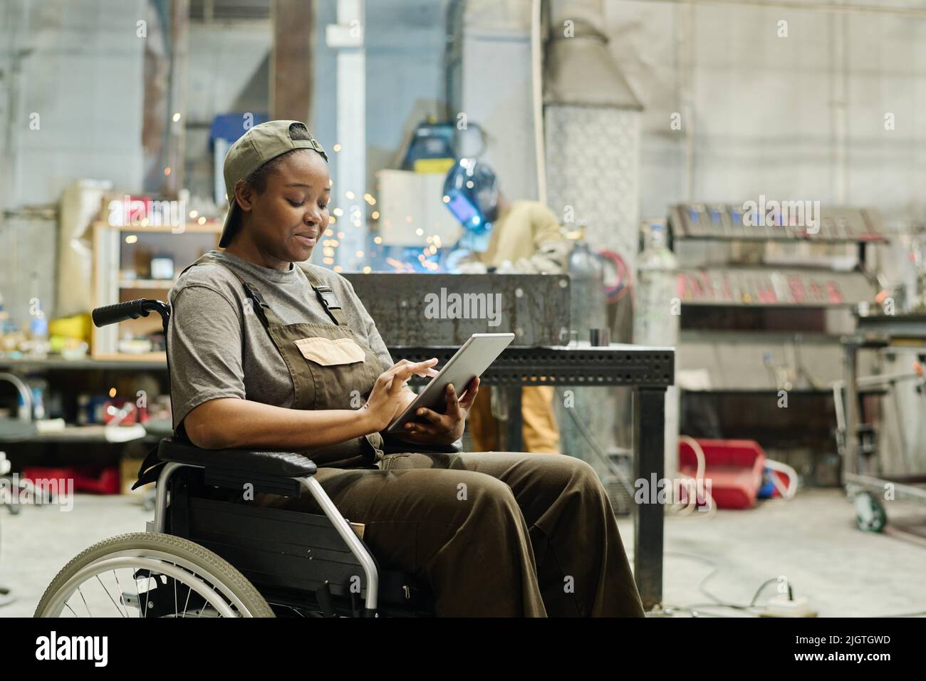 African female worker with disability using digital tablet at work ...