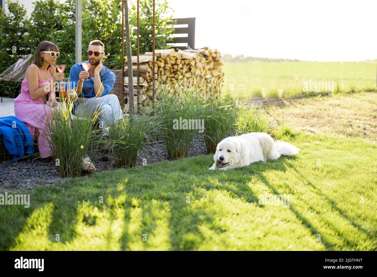 Stylish couple spend summer time with dog at the backyard Stock Photo ...