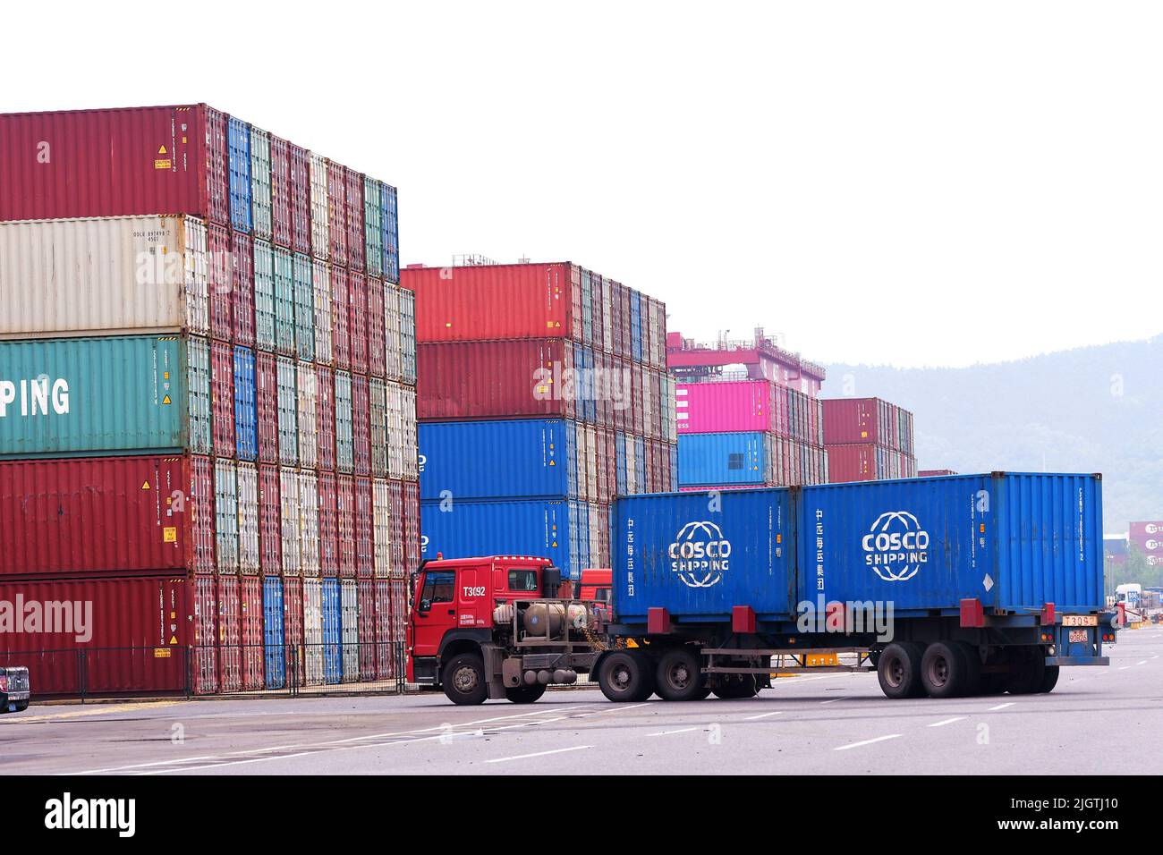 QINGDAO, CHINA - JULY 13, 2022 - Vehicles transport containers at the ...