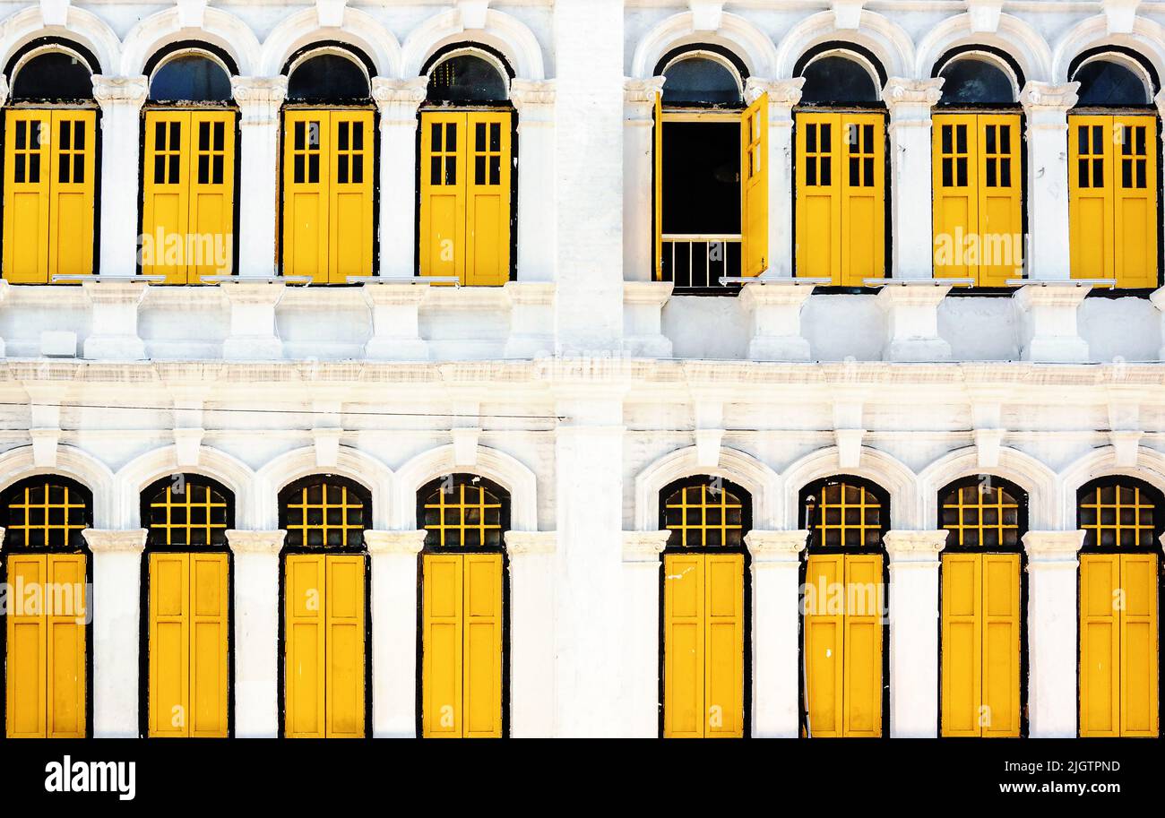 Yellow elongated windows with shatters on the facade of the old ...