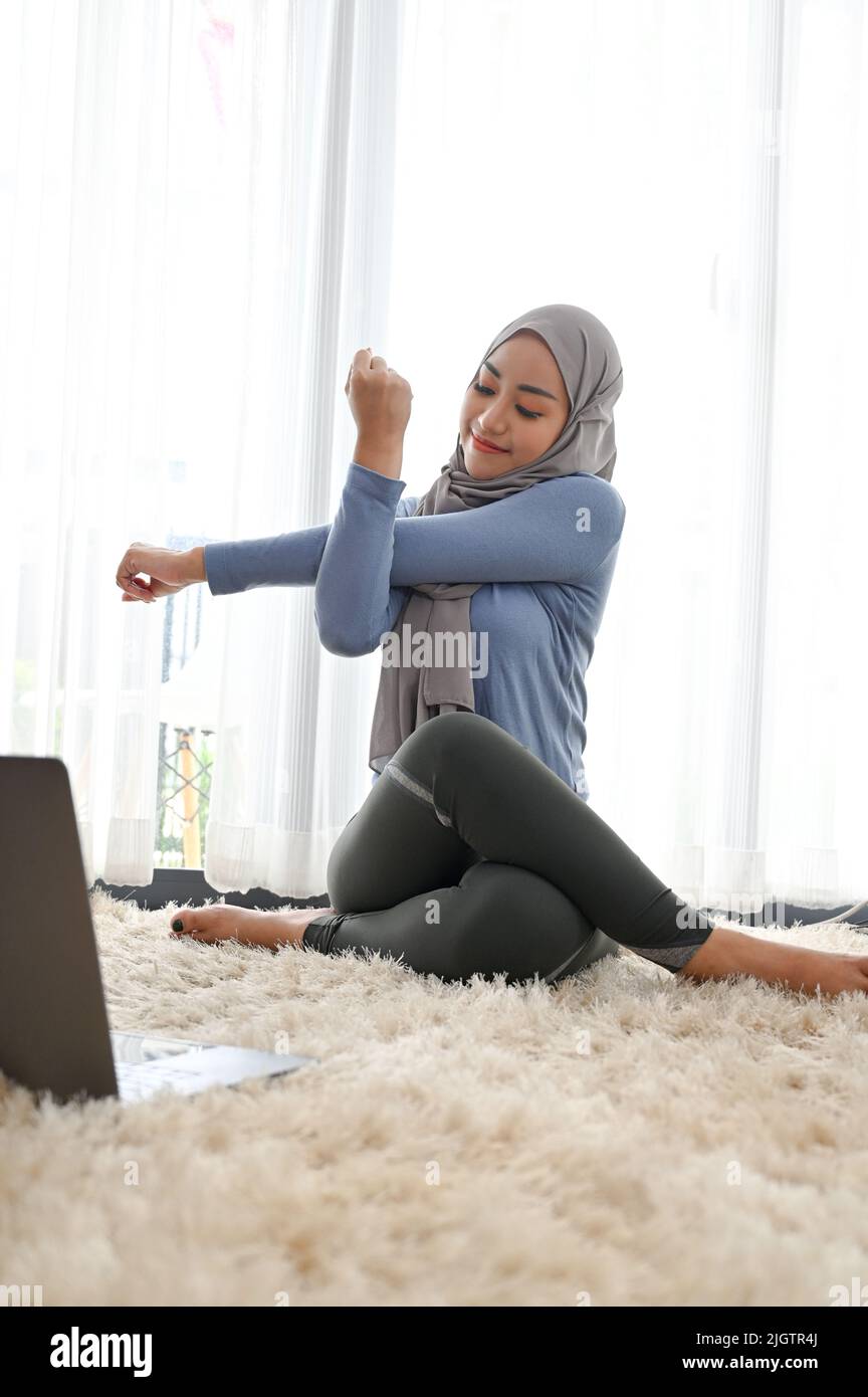 Healthy Asian Muslim woman wearing hijab relaxes practicing yoga ...