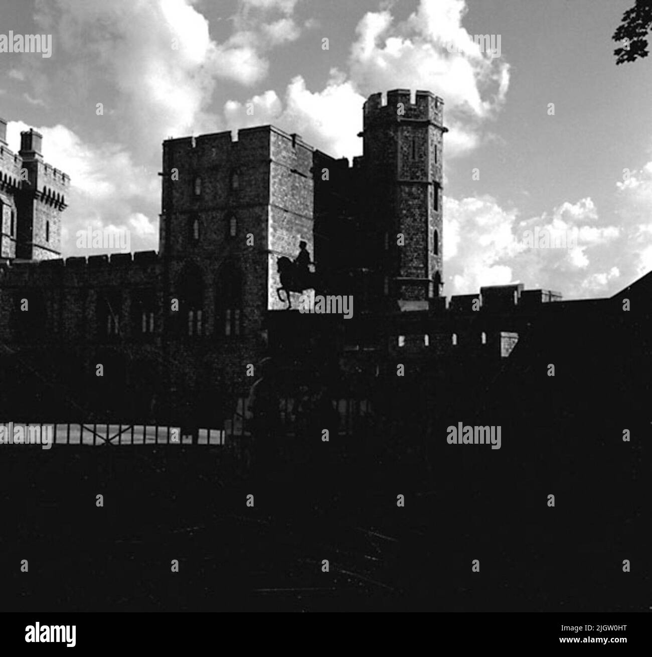 Two women can see faintly in front of the fences of a castle. The ...