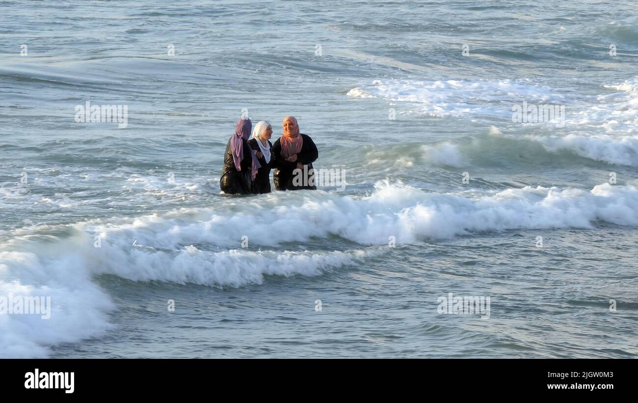 Palestinian women stand in the waters of the Mediterranean Sea during ...