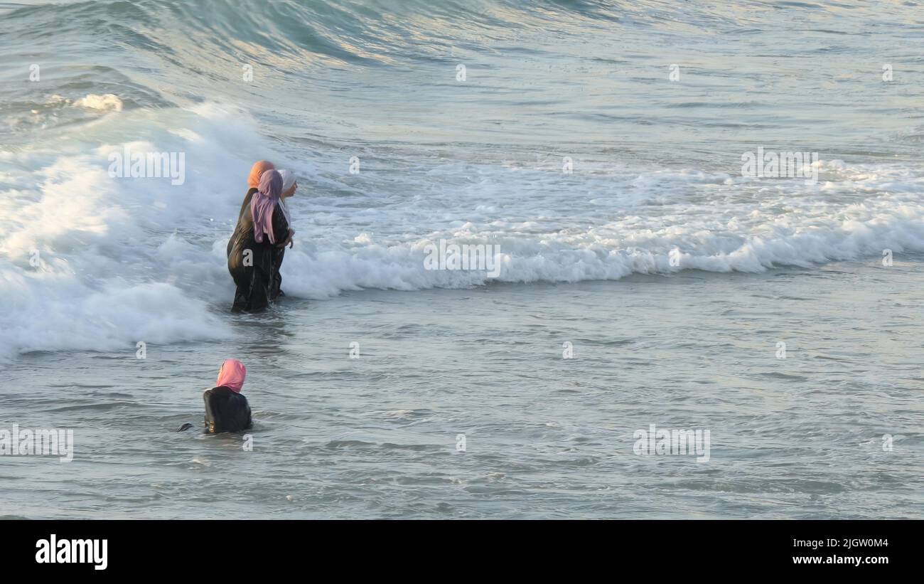 Palestinian women stand in the waters of the Mediterranean Sea during ...