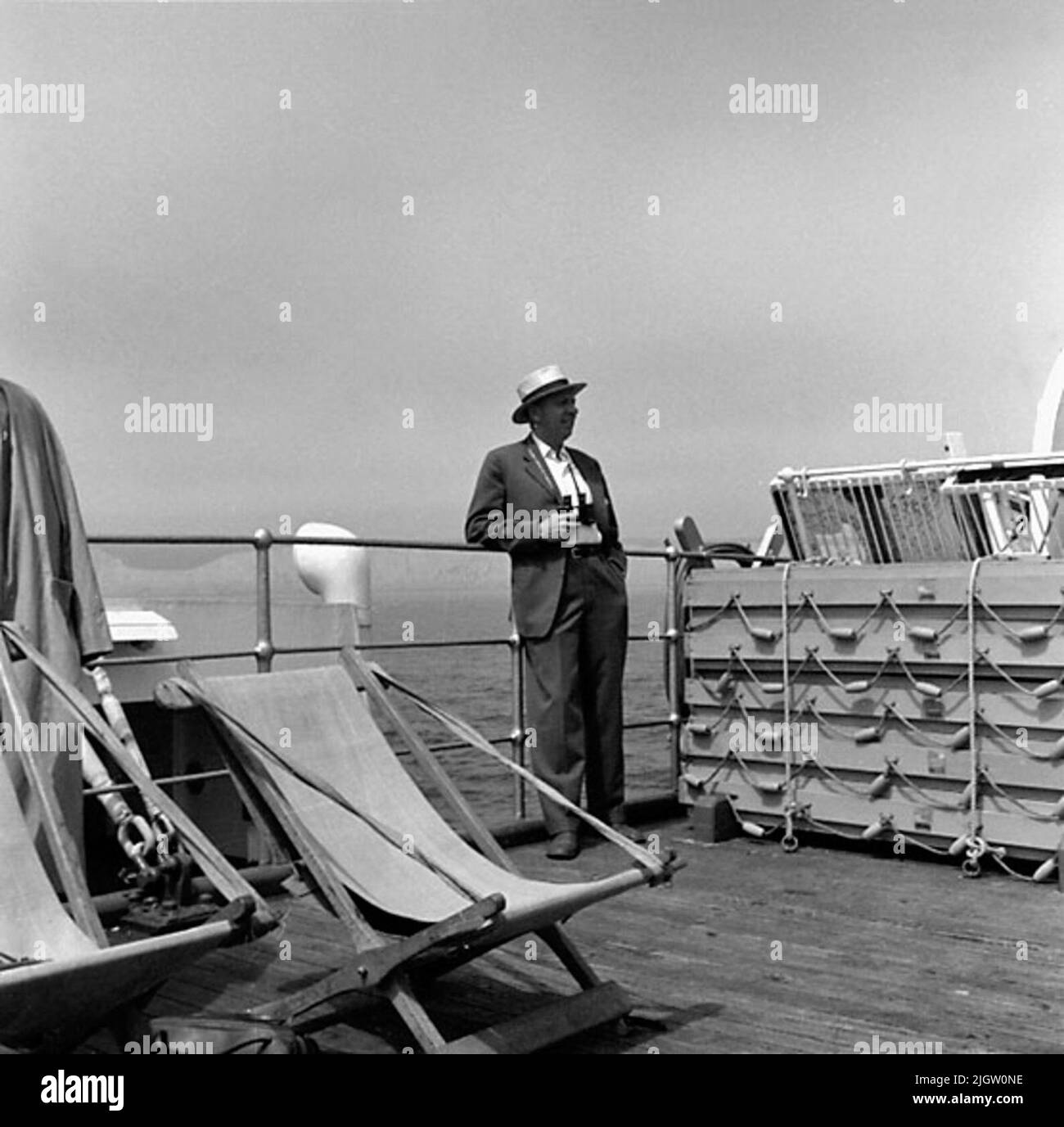 A man stands on the sun deck on a ship. Behind him lies a sea and on ...