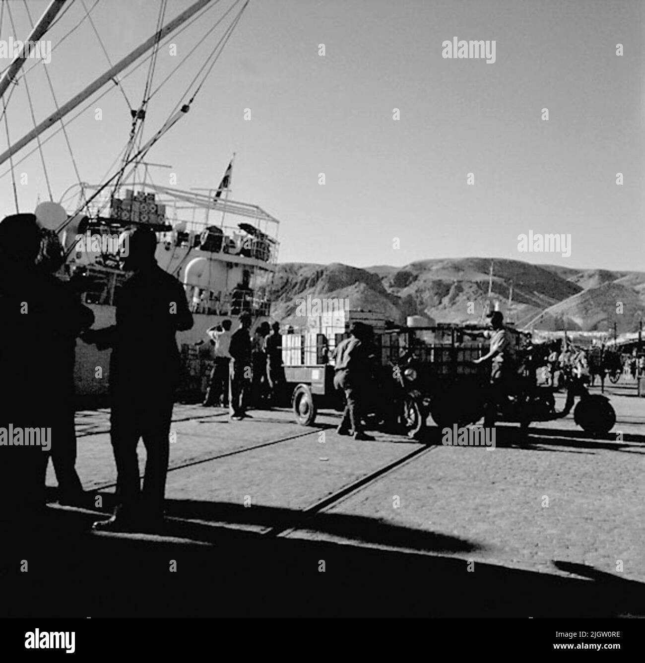 A boat is located in a harbor. On the quay there are several men and ...