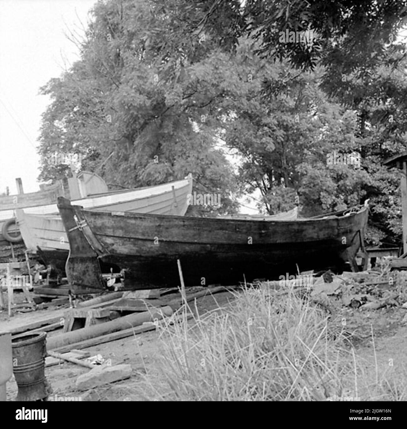 Three boats are commissioned on a beach in a boat yard. Above the boats ...