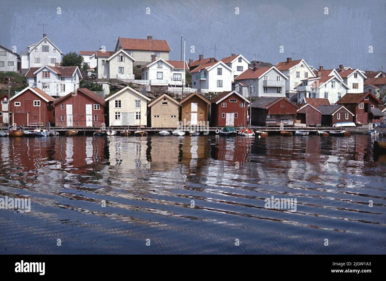 A community by the sea with boathouses closest to the waterline, where ...