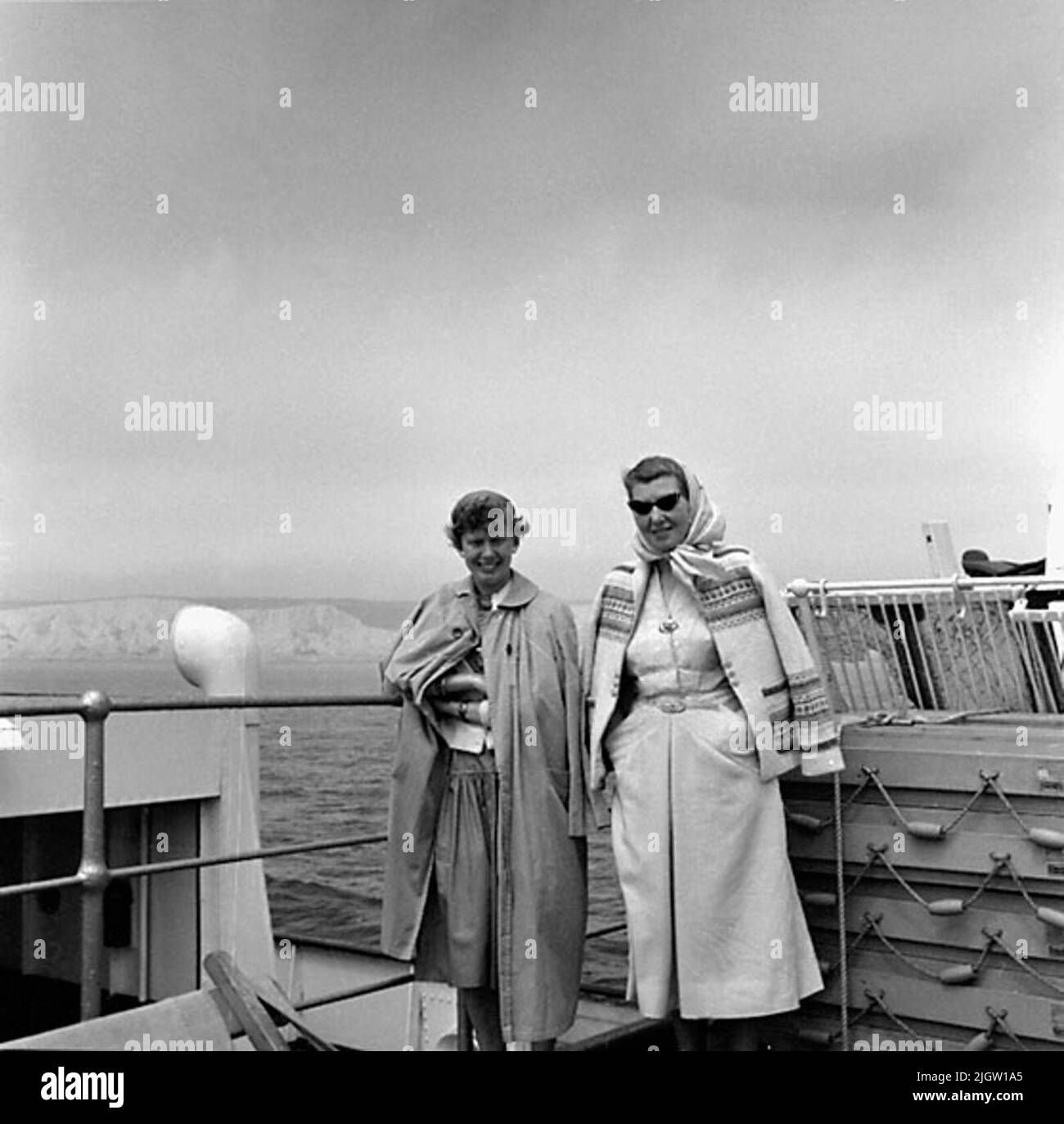 Two women stand on deck on a ship. Behind them lies a sea and on the ...