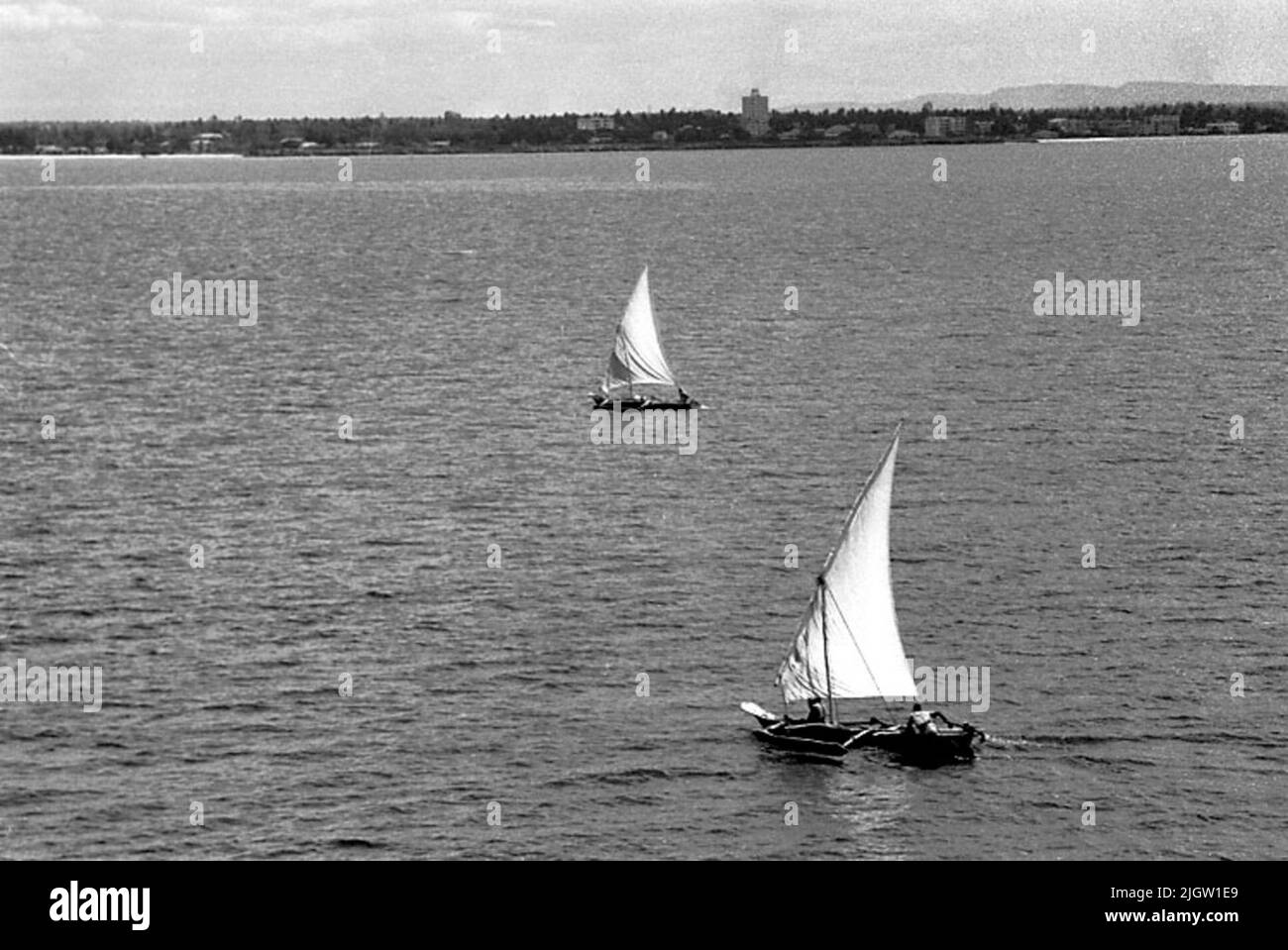 Two sailboats sail in a sea bay. Inside the bay is a society. African ...