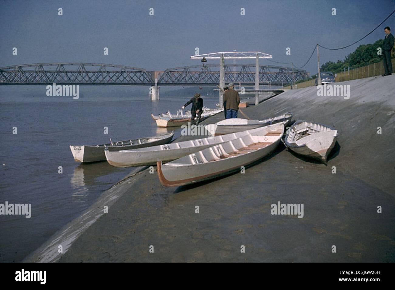 Several boats are commissioned on a concrete "beach". Three men are ...