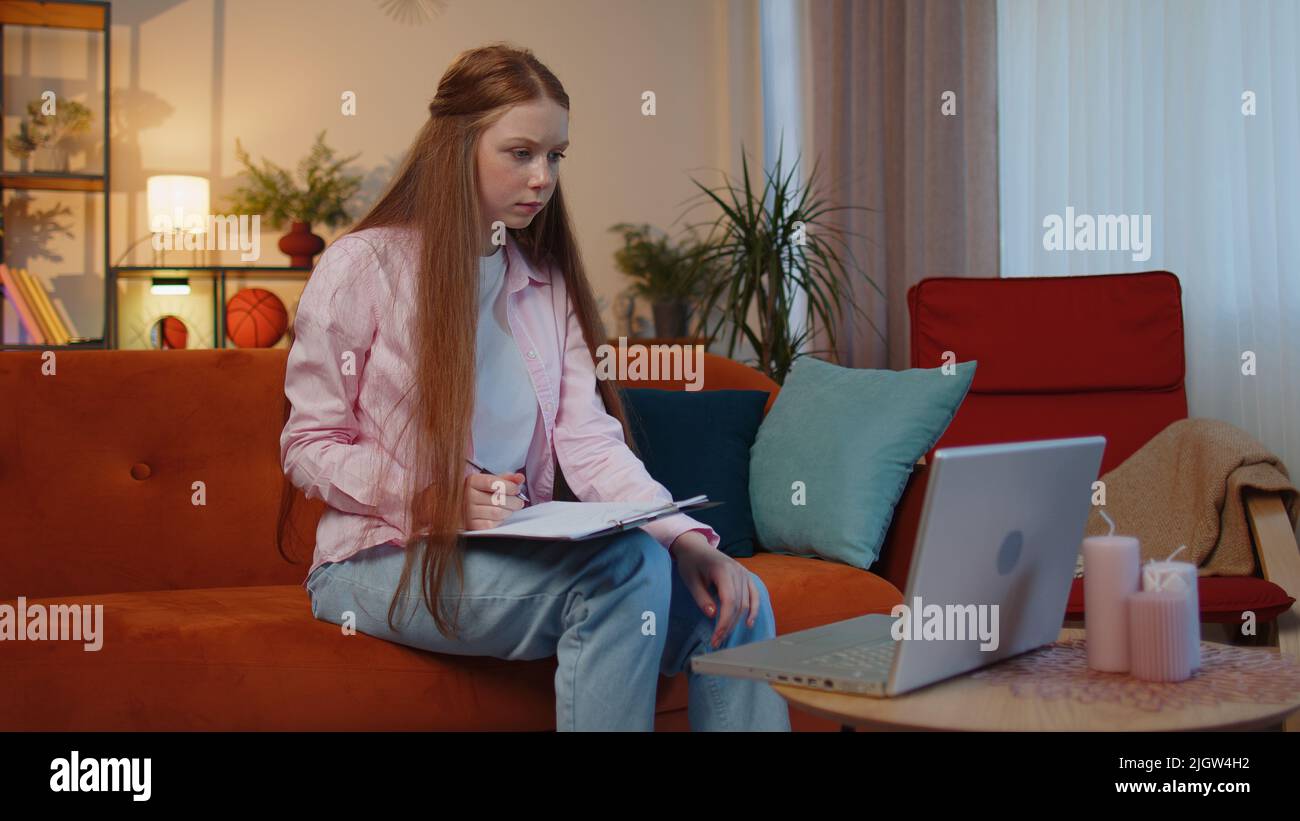 Sad teen child girl working online on laptop analysing paperwork graphs ...