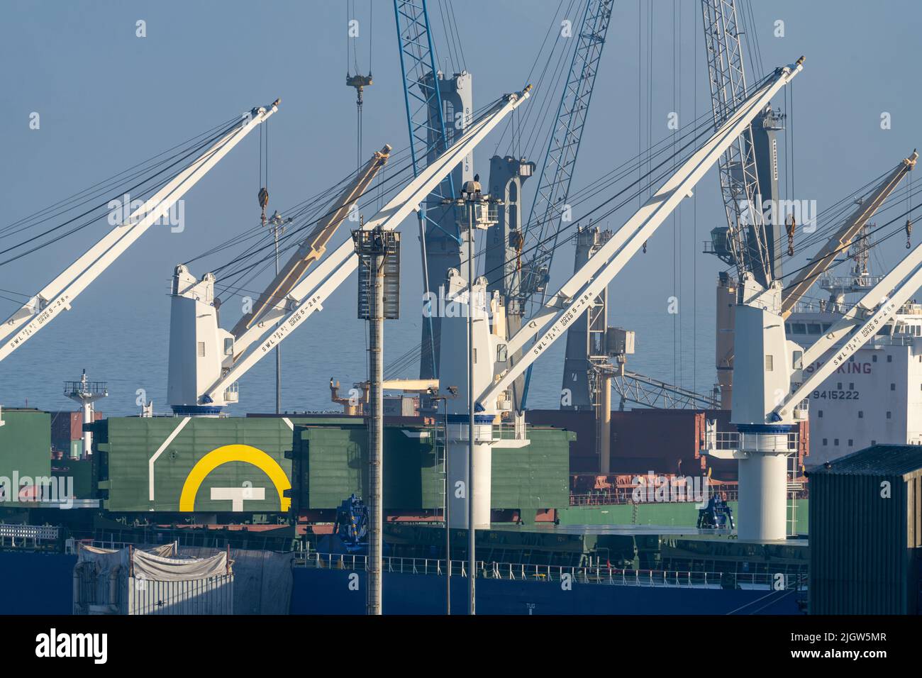 Cargo loading cranes on a bulk cargo freighter at the loading dock in ...