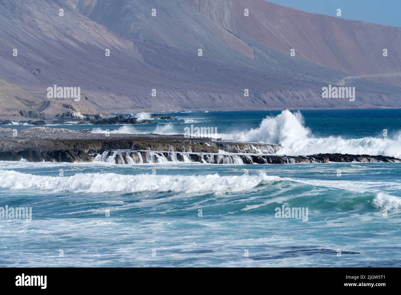 Waves crash on the rocky shoreline of tne coast of the Pacific Ocean ...