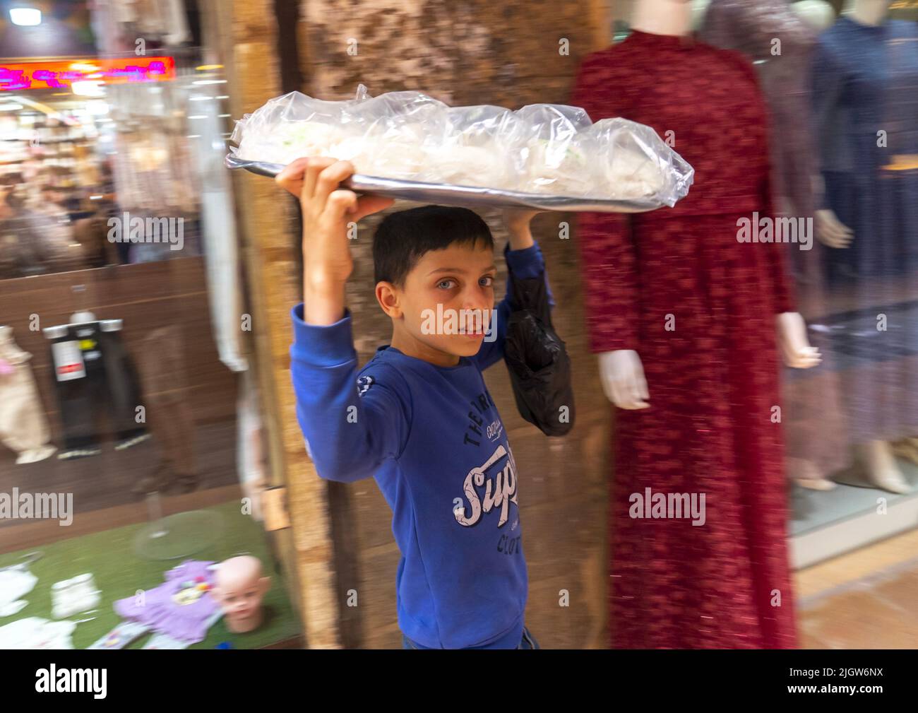 Young syrian boy carrying food on his head in the souk, North ...