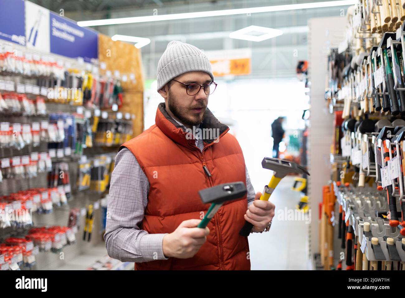 a man chooses a new hammer in a construction hypermarket Stock Photo ...