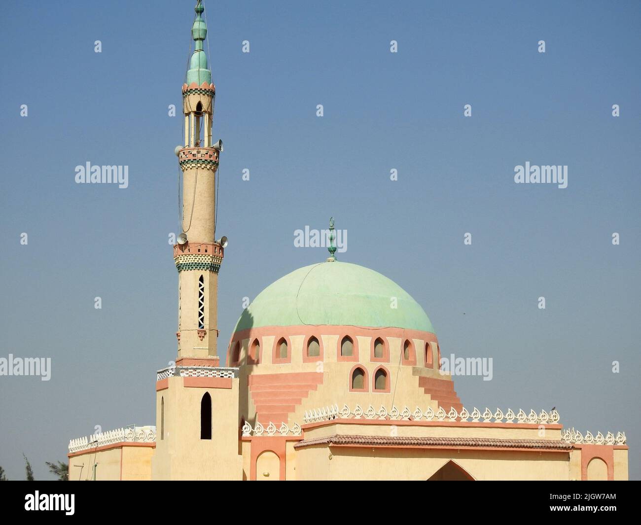 An Islamic mosque with a blue clear sunny summer sky with a green dome ...