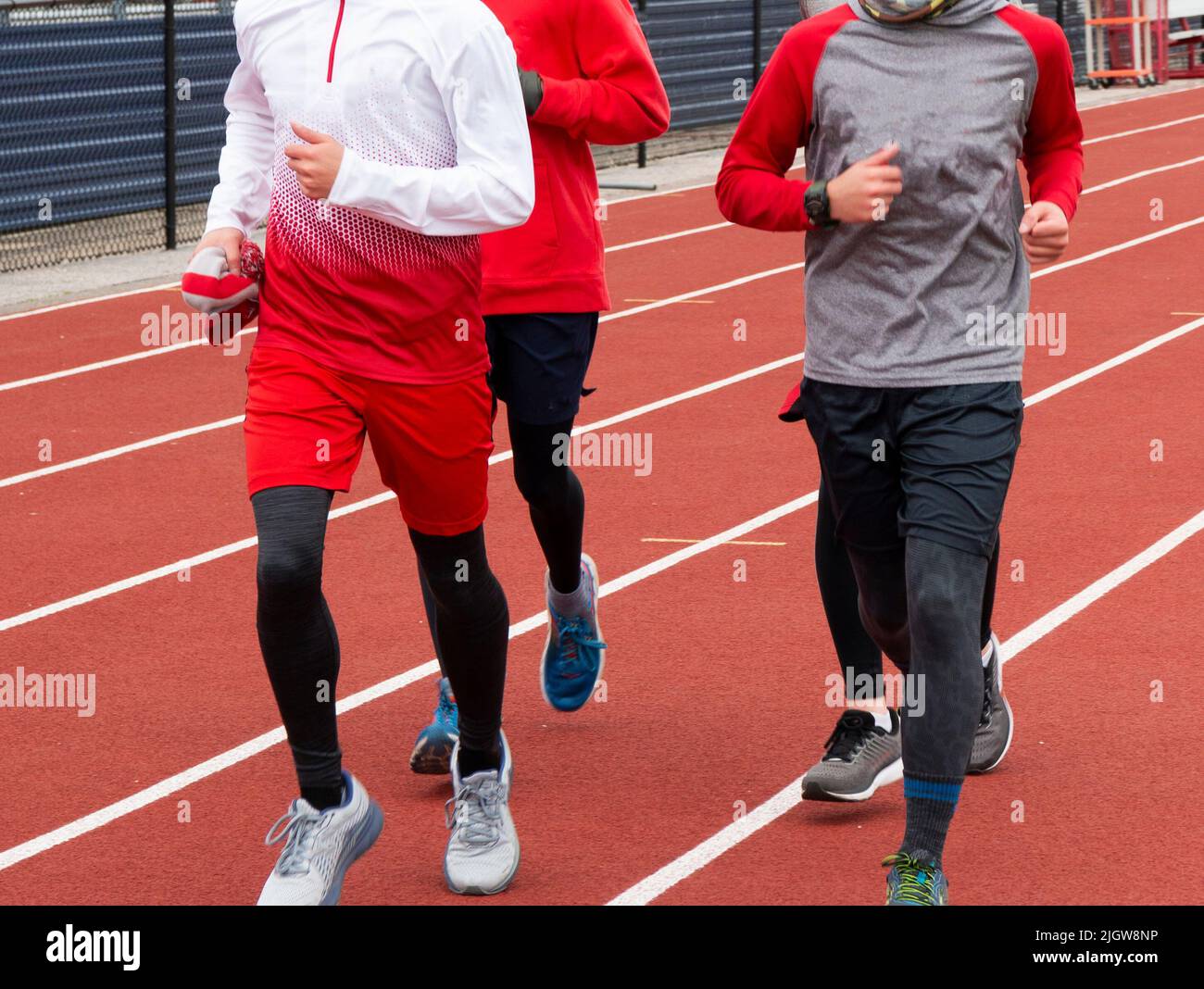A group of high school boys running together on a track outdoor in the ...