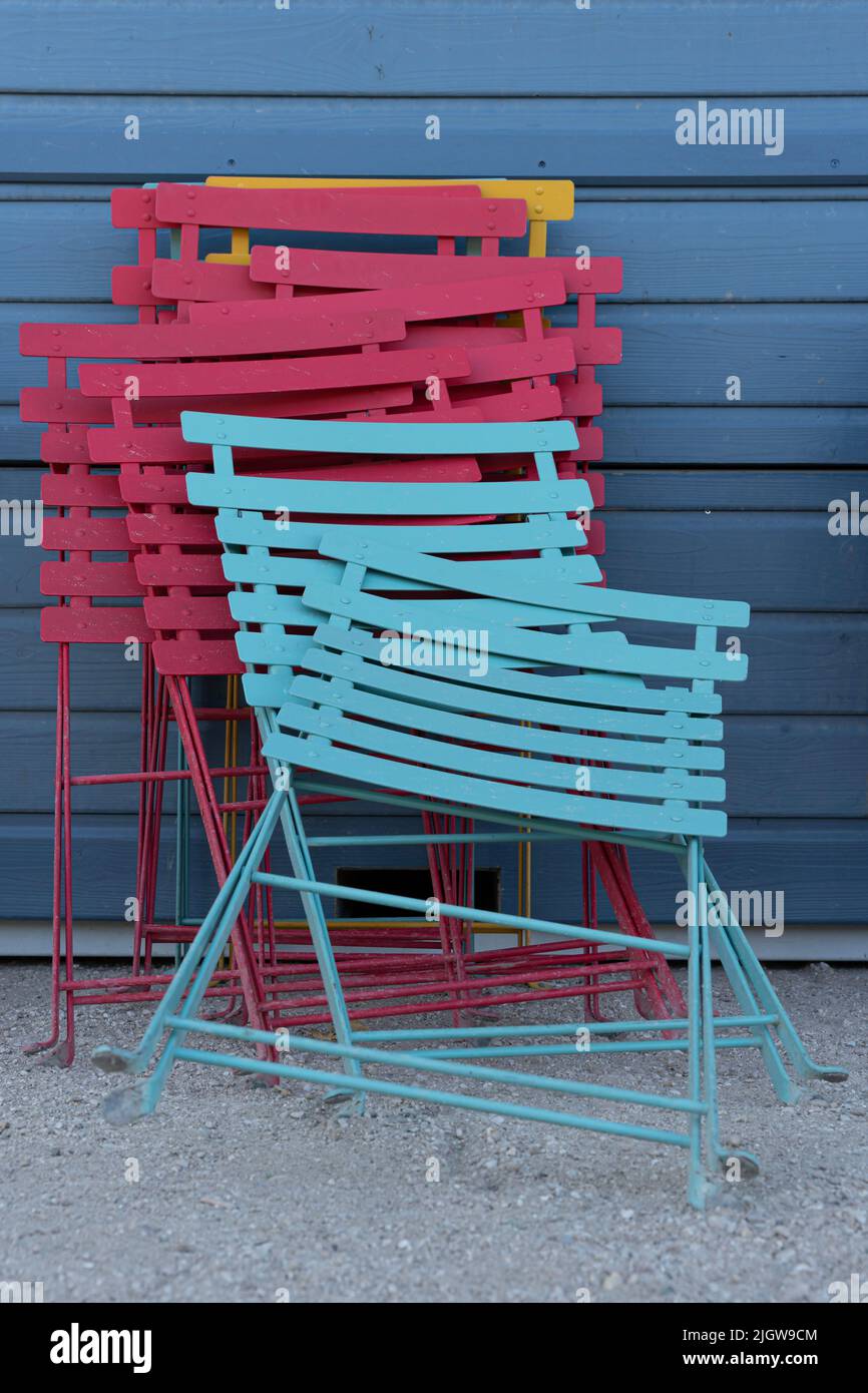 A closed blue wooden cabin with colorful closed chairs, tables on the ...