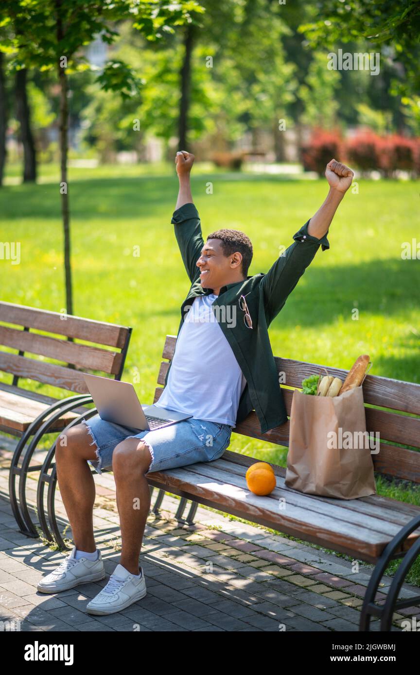 Guy sitting on bench stretching raising hands Stock Photo - Alamy