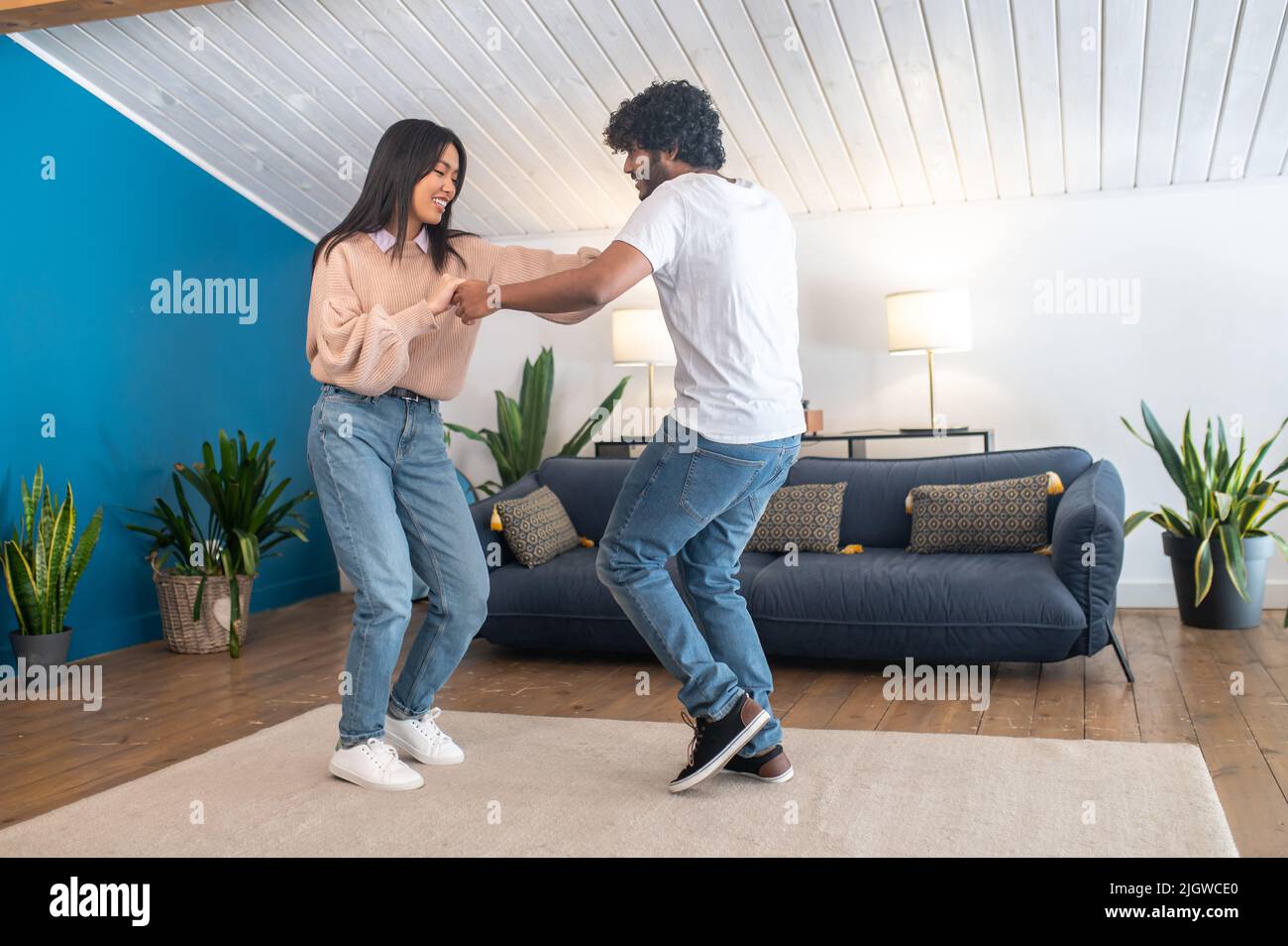 Cute young couple looking happy while dancing Stock Photo - Alamy