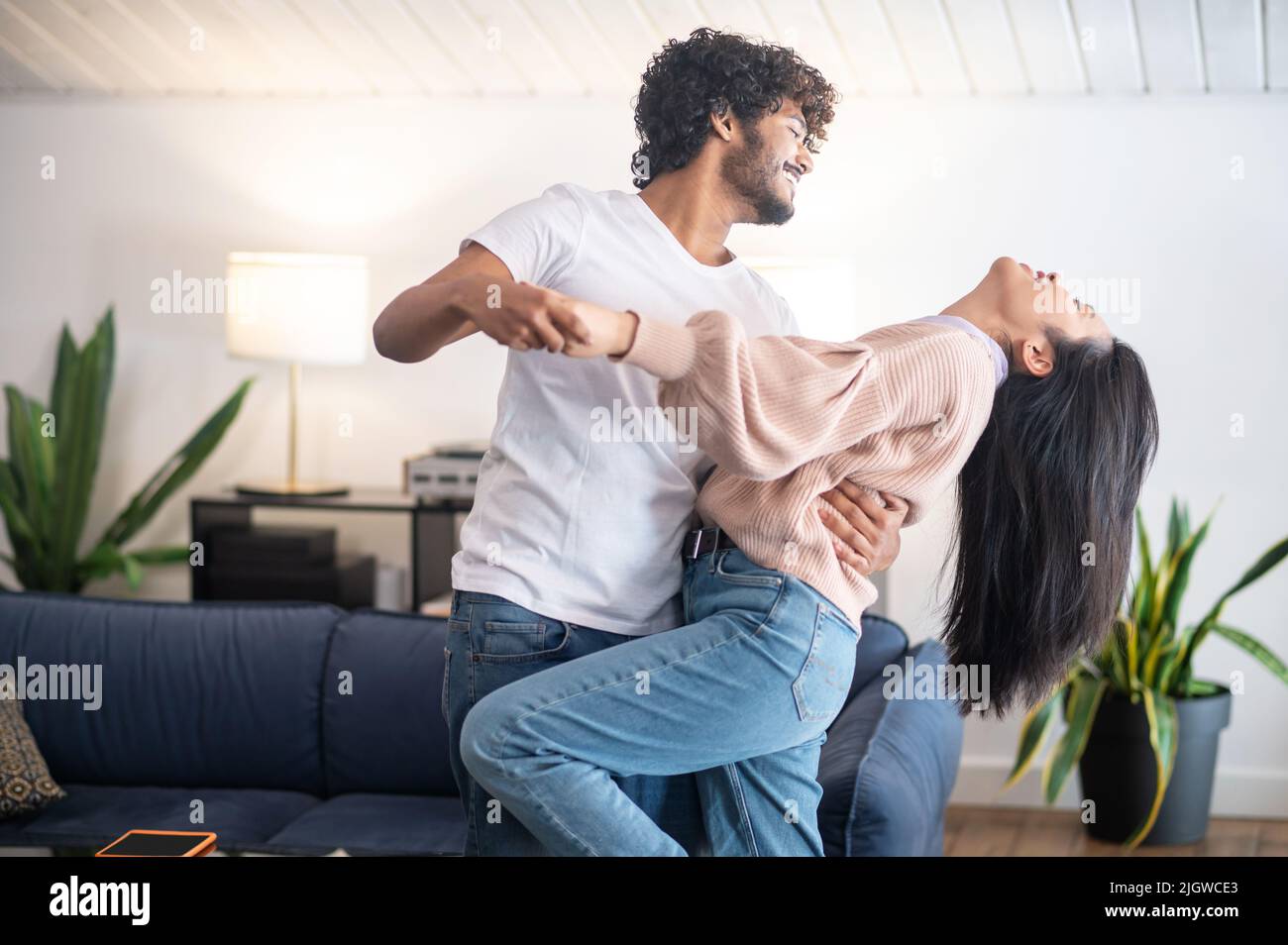 Cute young couple looking happy while dancing Stock Photo - Alamy