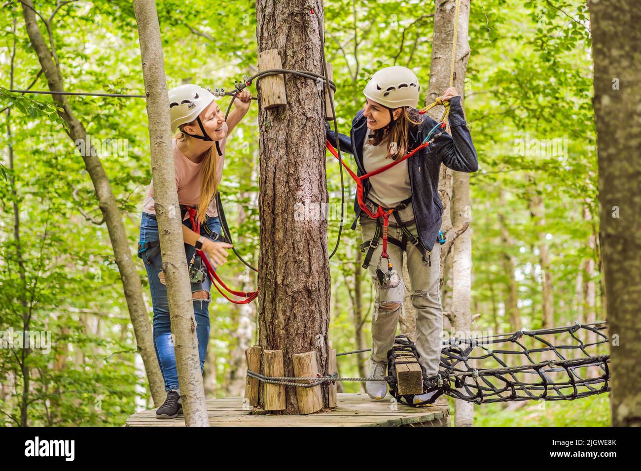 Two women girls female gliding climbing in extreme road trolley zipline ...