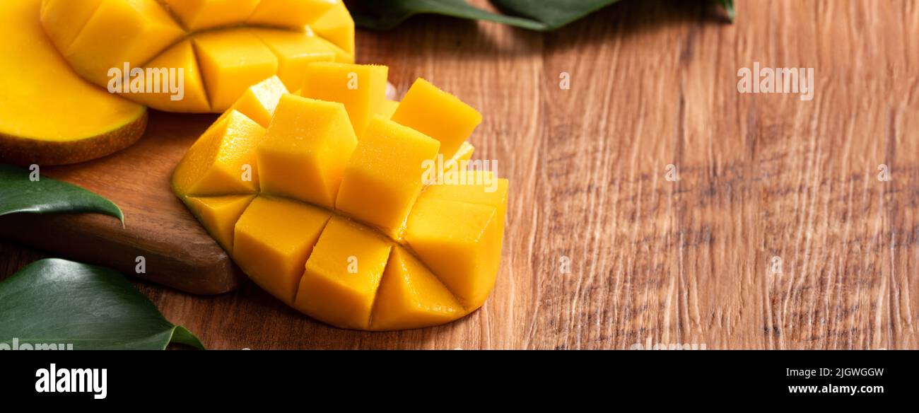 Mango. Close up of fresh ripe mango fruit with leaves over dark wooden ...