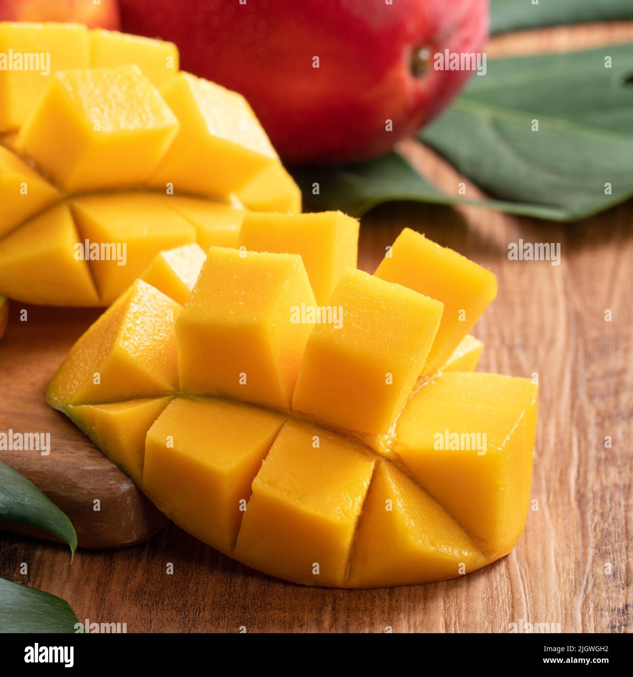 Mango. Close up of fresh ripe mango fruit with leaves over dark wooden ...