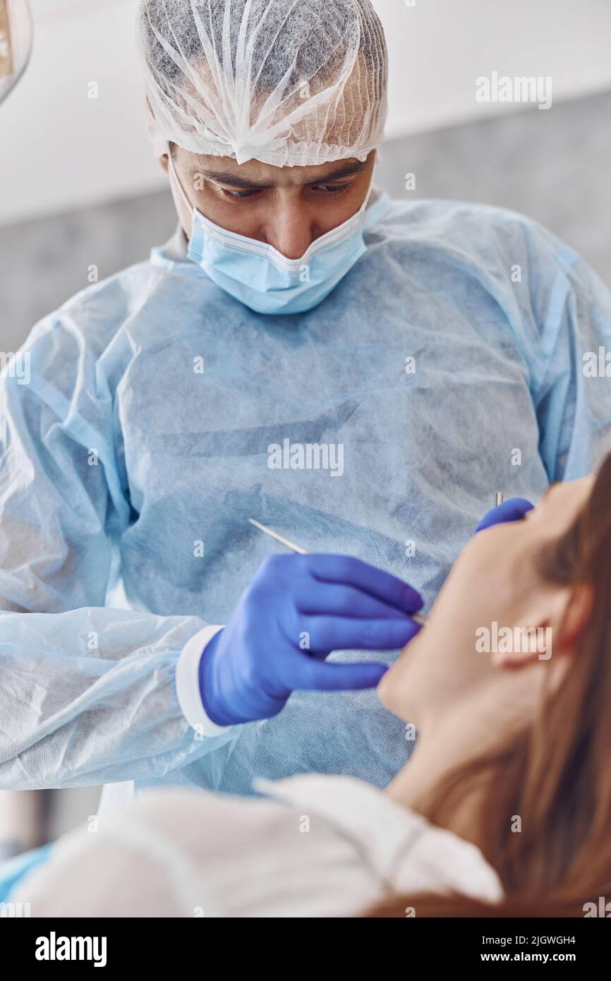 Professional doctor is doing tooth surgery to happy caucasian woman in ...