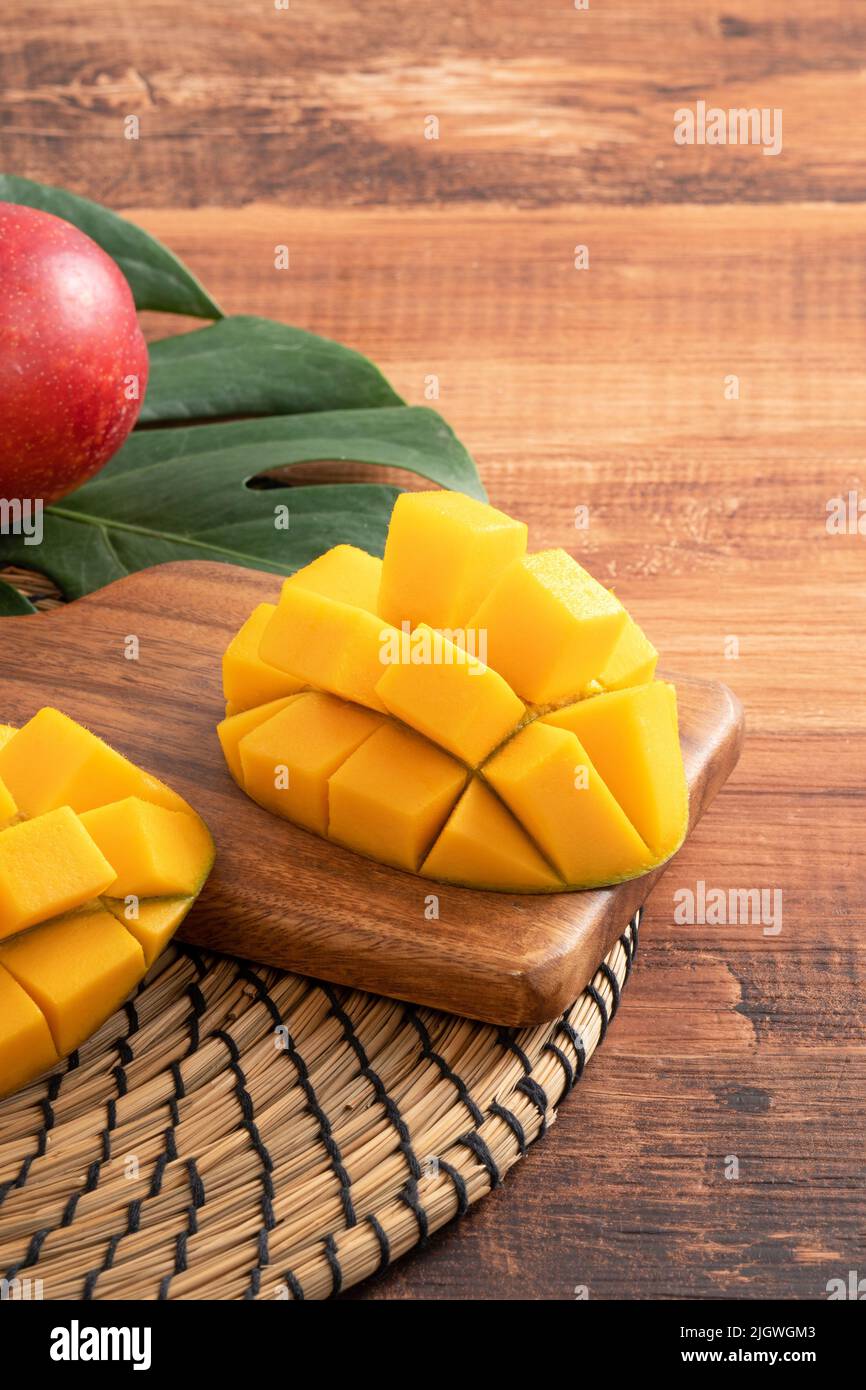 Mango. Close up of fresh ripe mango fruit with leaves over dark wooden ...