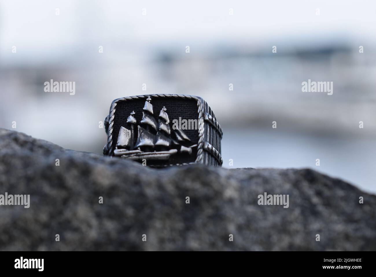 A selective focus shot of silver pirate ship ring on a rock on blur ...